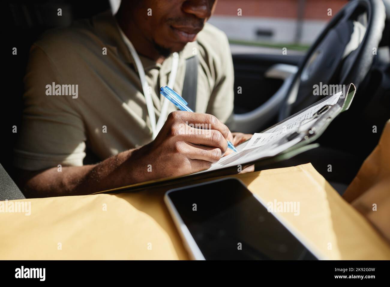 Close up of delivery worker filling in forms and documents in van,copy ...