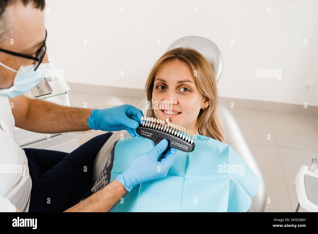 Tooth whitening. Dentist working with teeth color shades guide. Dentistry. Doctor checking teeth ...