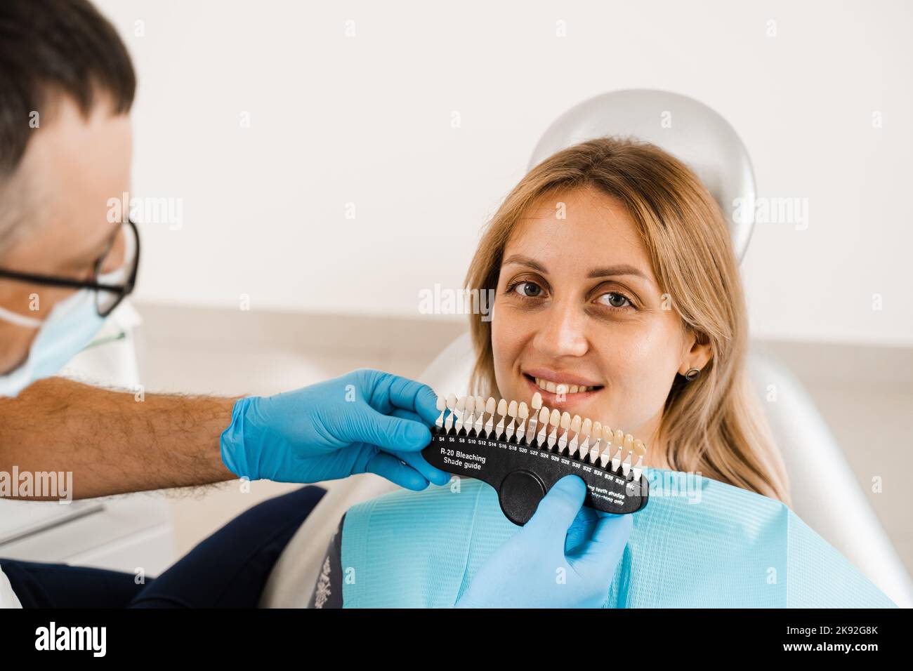 Tooth whitening. Dentist working with teeth color shades guide ...