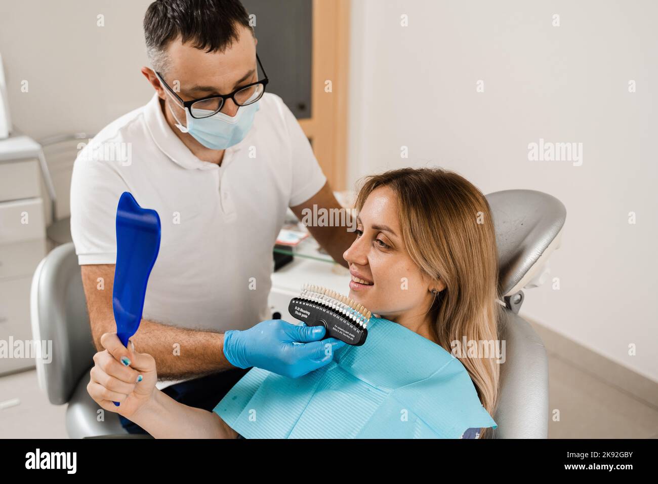 Teeth whitening. Patient looking at teeth color shades guide. Dentistry ...