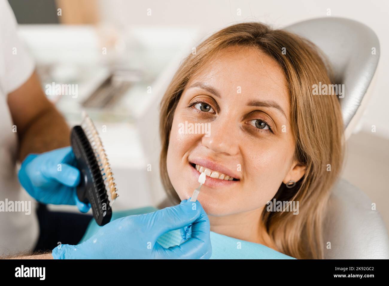 Teeth color shades guide close-up with woman patient. Tooth whitening. Dentist working with ...