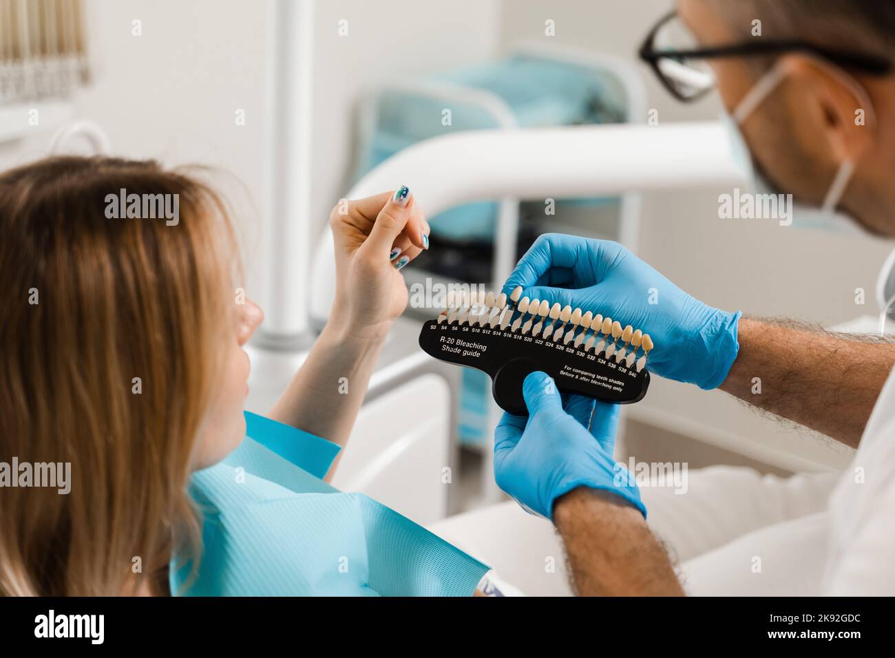 Woman looking at veneers or implants teeth color matching samples in ...