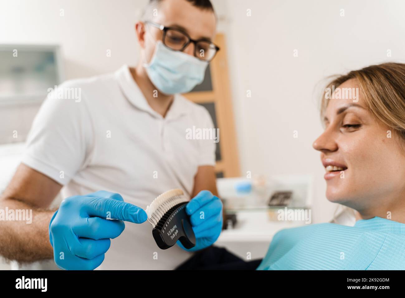 Woman looking at veneers or implants teeth color matching samples in doctor hands. Dentistry ...