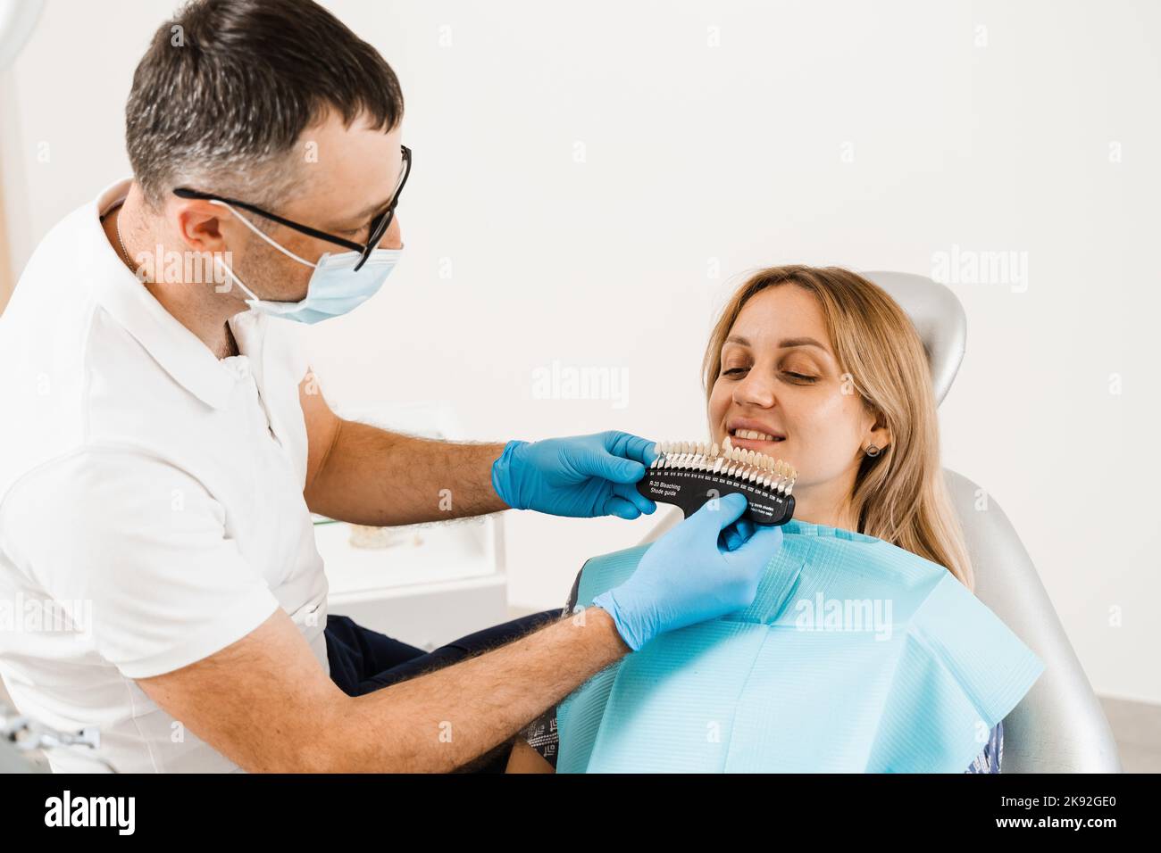 Tooth whitening. Dentist working with teeth color shades guide ...