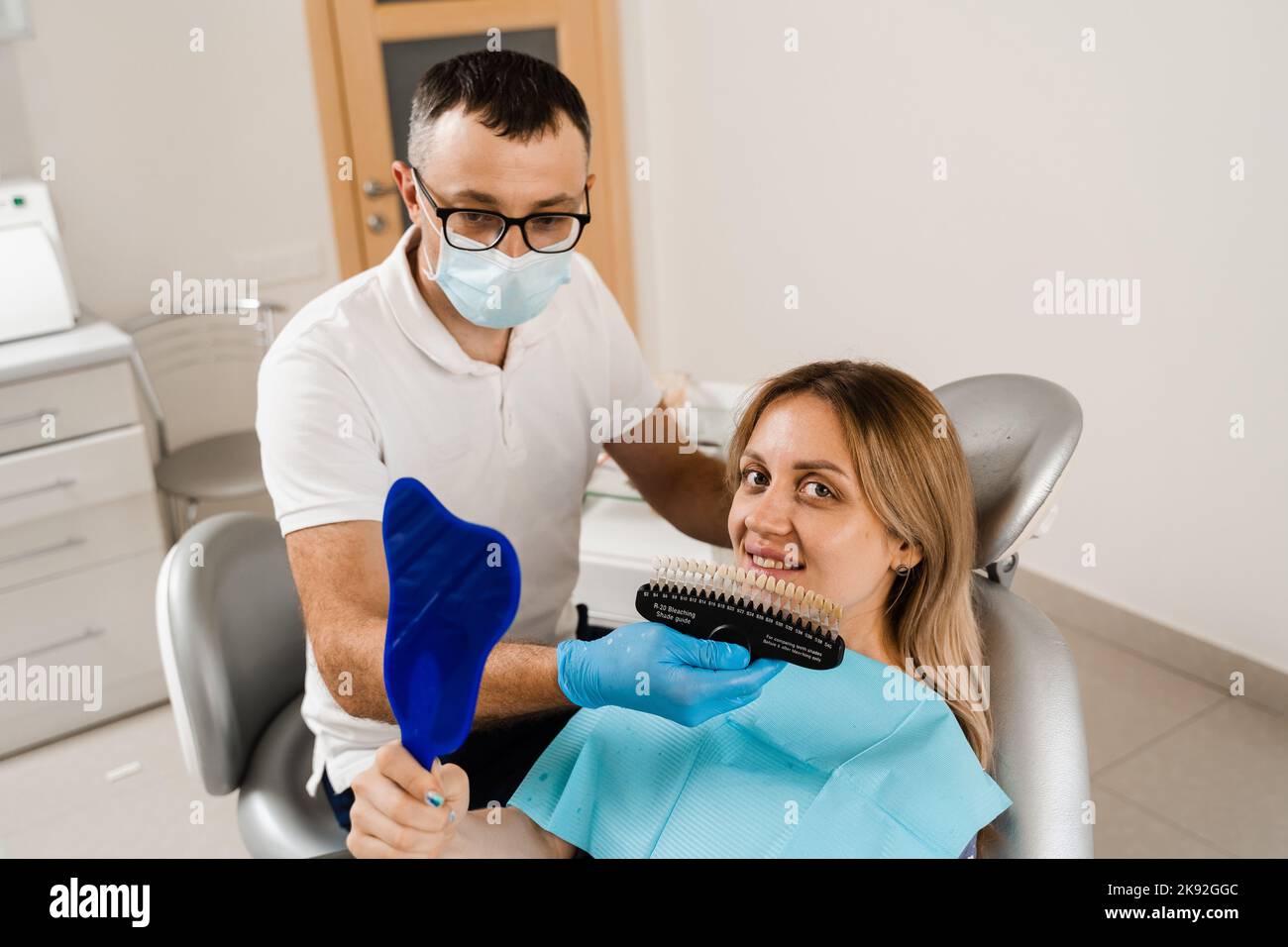 Teeth whitening. Patient looking at teeth color shades guide. Dentistry ...