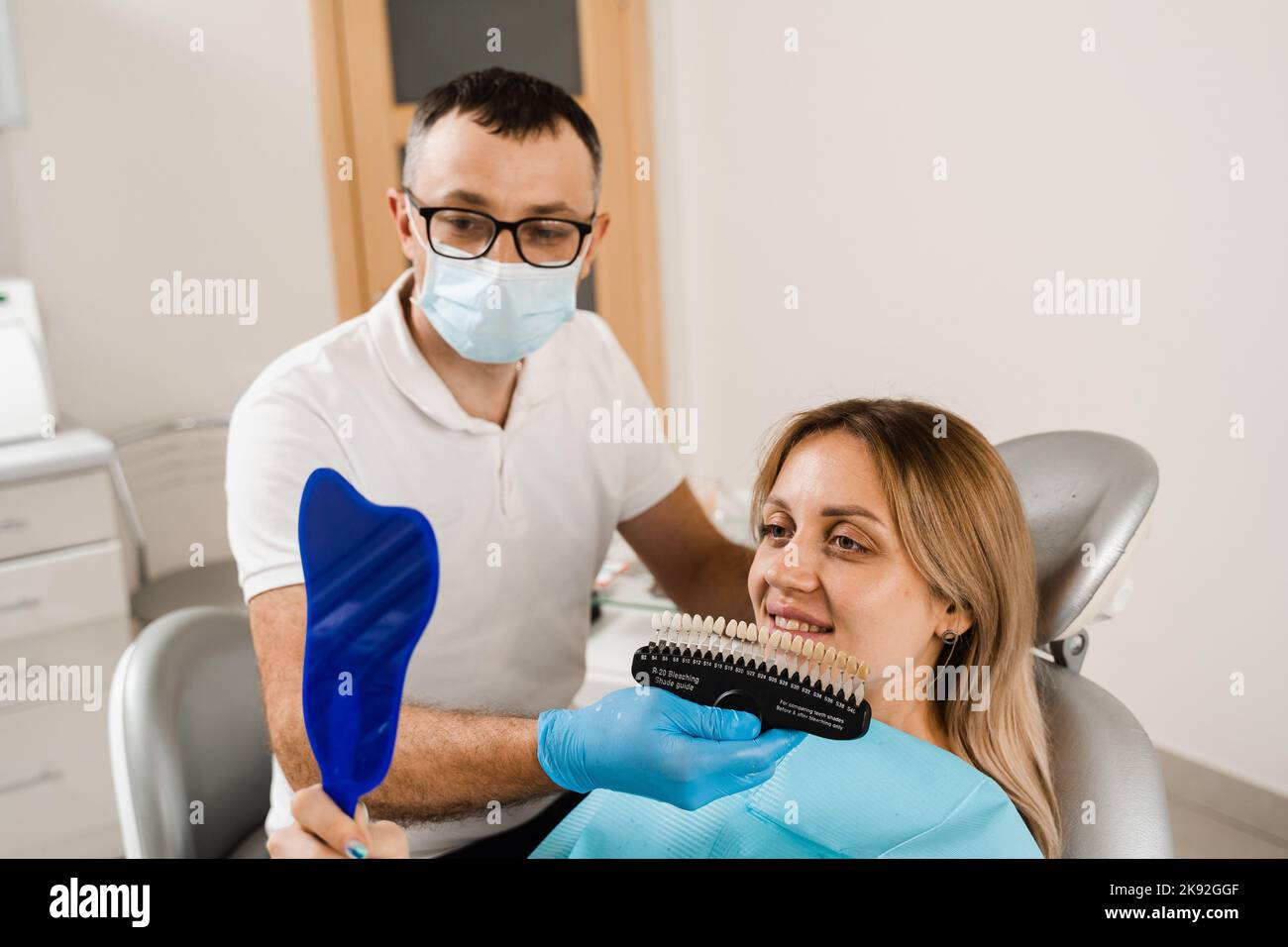 Teeth whitening. Patient looking at teeth color shades guide. Dentistry ...