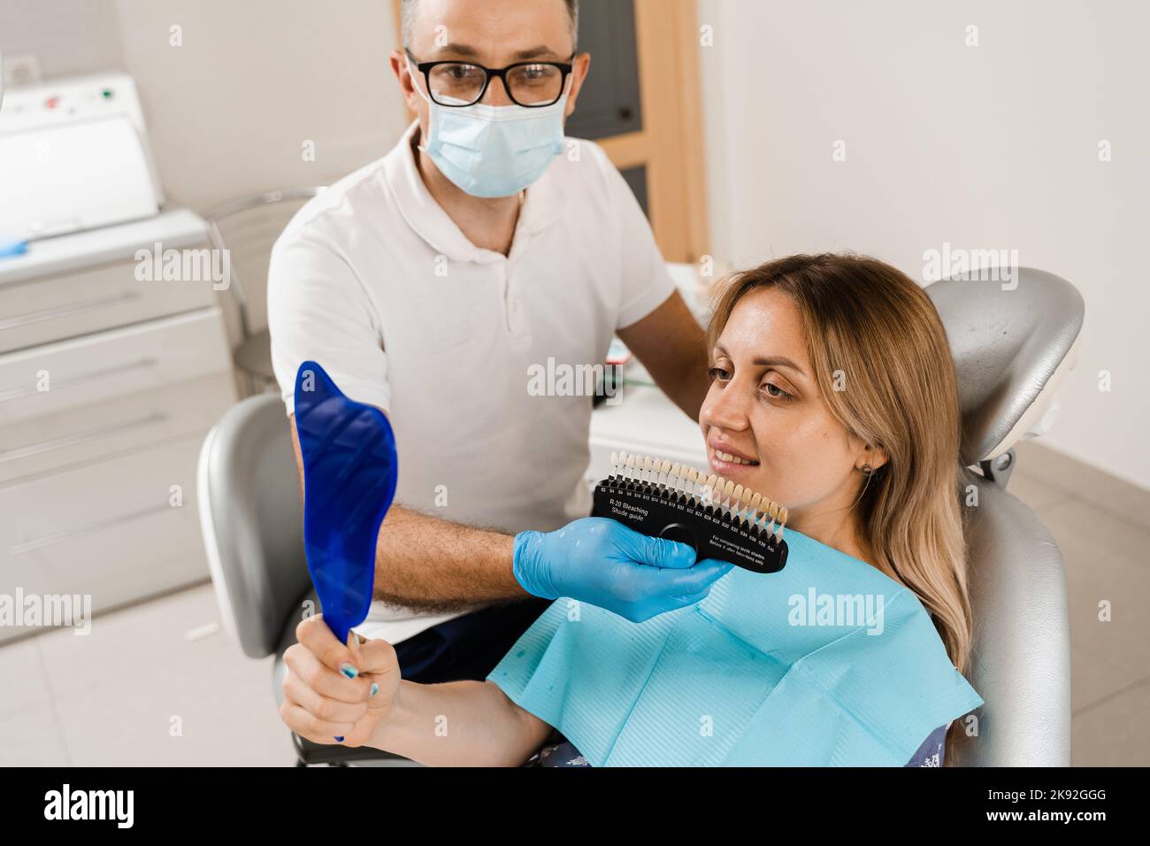 Teeth whitening. Patient looking at teeth color shades guide. Dentistry ...