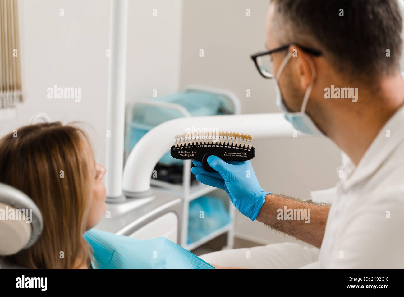 Woman looking at veneers or implants teeth color matching samples in doctor hands. Dentistry ...