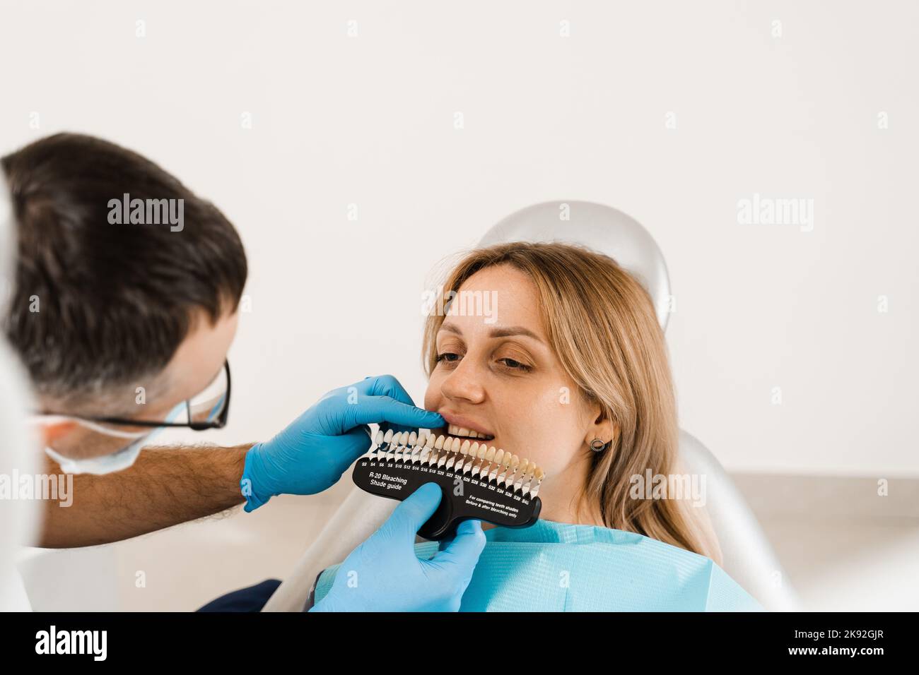 Tooth whitening. Dentist working with teeth color shades guide. Dentistry. Doctor checking teeth ...