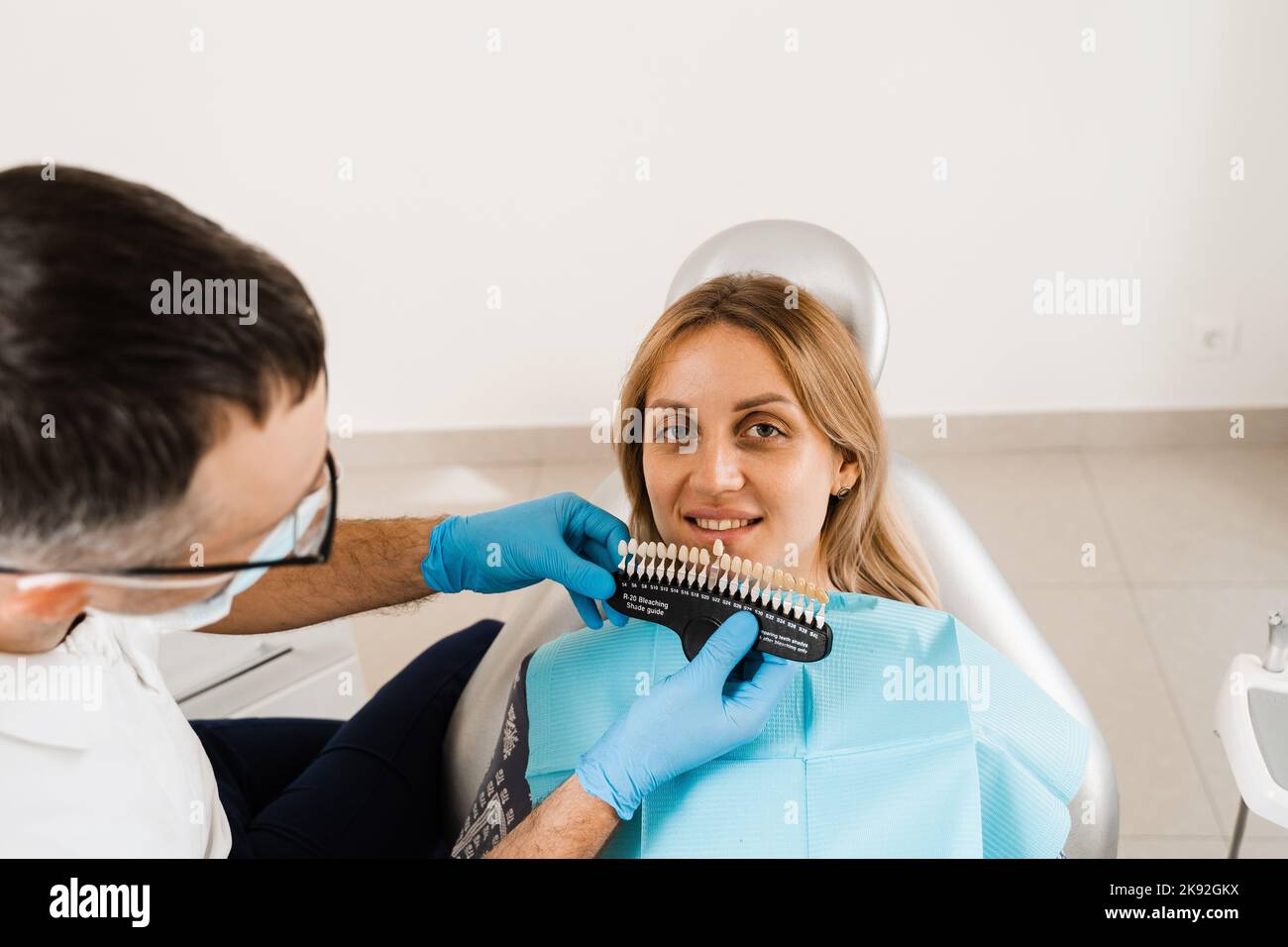 Tooth whitening. Dentist working with teeth color shades guide. Dentistry. Doctor checking teeth ...