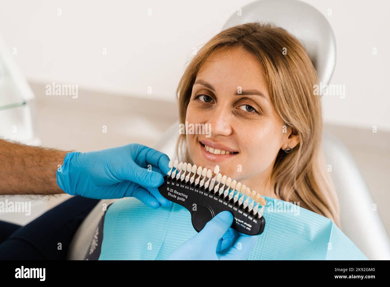 Tooth whitening. Dentist working with teeth color shades guide ...