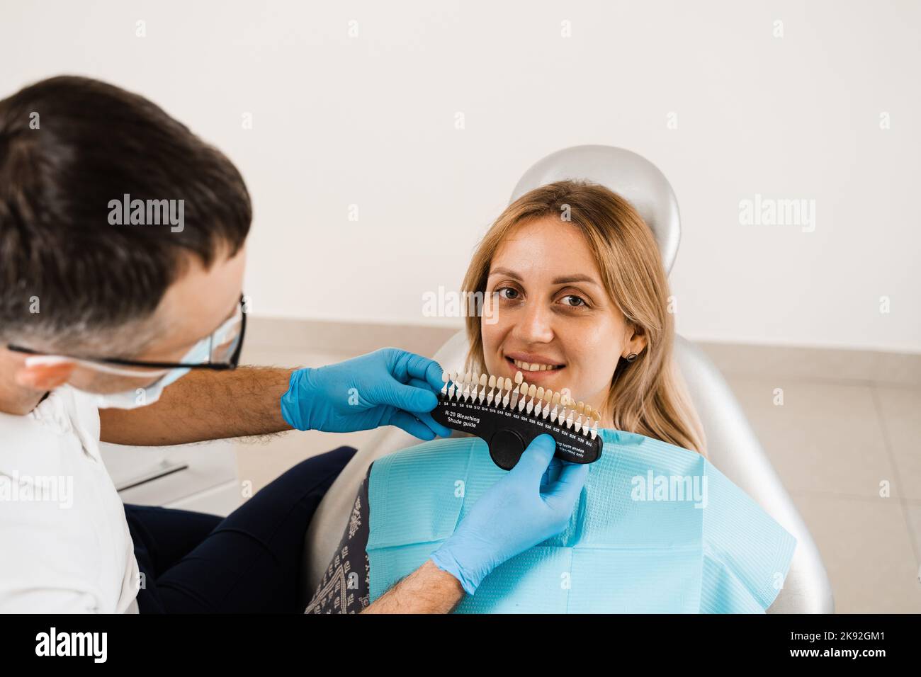 Tooth whitening. Dentist working with teeth color shades guide ...