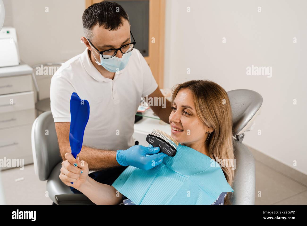 Teeth whitening. Patient looking at teeth color shades guide. Dentistry. Doctor checking tooth ...