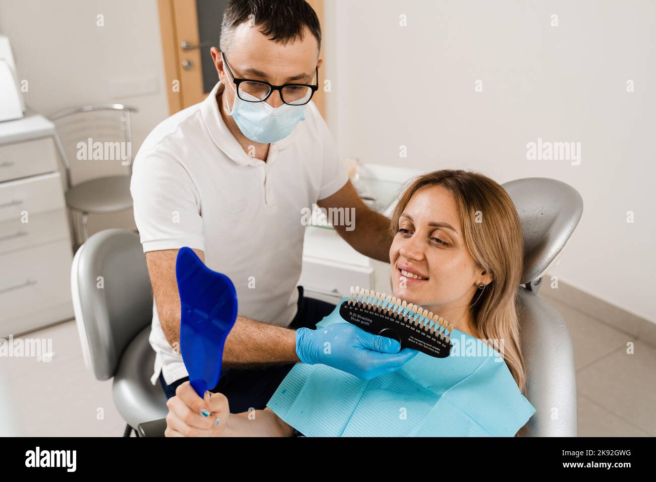 Teeth whitening. Patient looking at teeth color shades guide. Dentistry ...