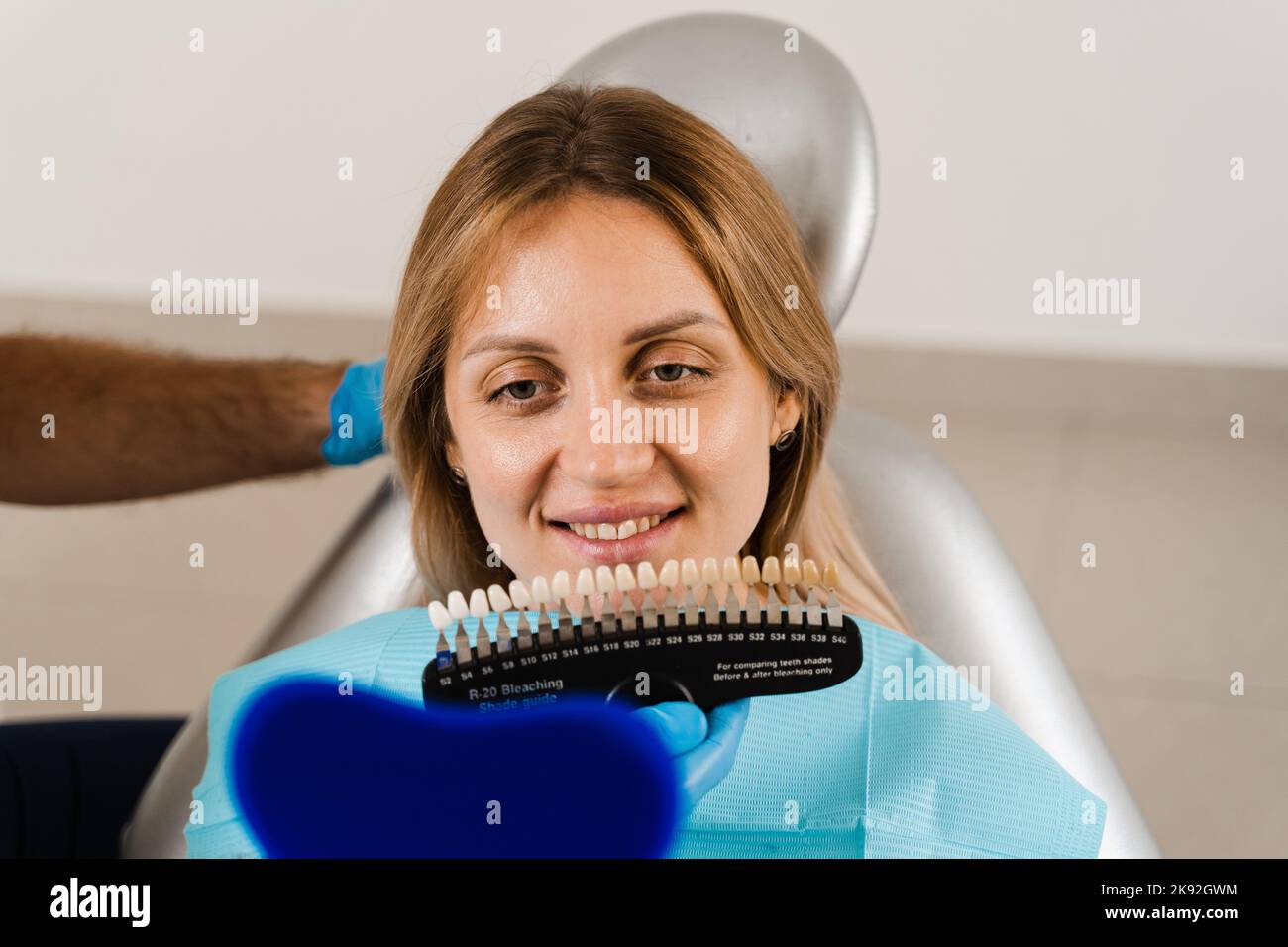 Teeth whitening. Patient looking at teeth color shades guide. Dentistry. Doctor checking tooth ...