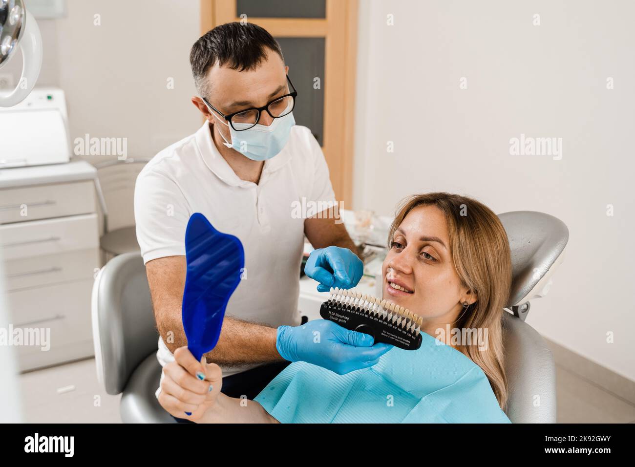 Teeth whitening. Dentist working with teeth color shades guide. Patient ...