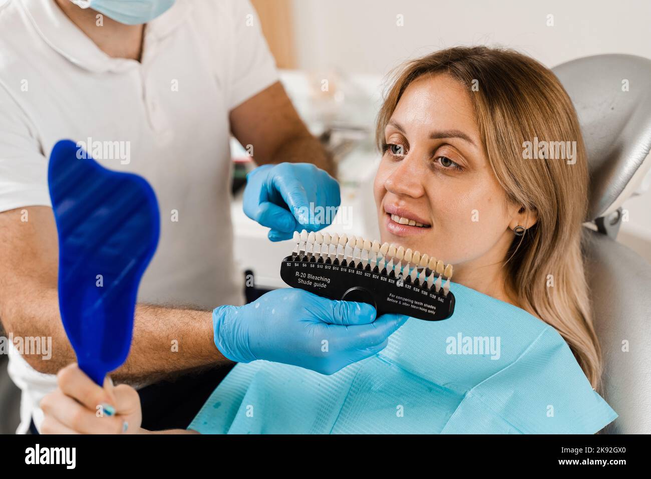 Teeth whitening. Dentist working with teeth color shades guide. Patient ...