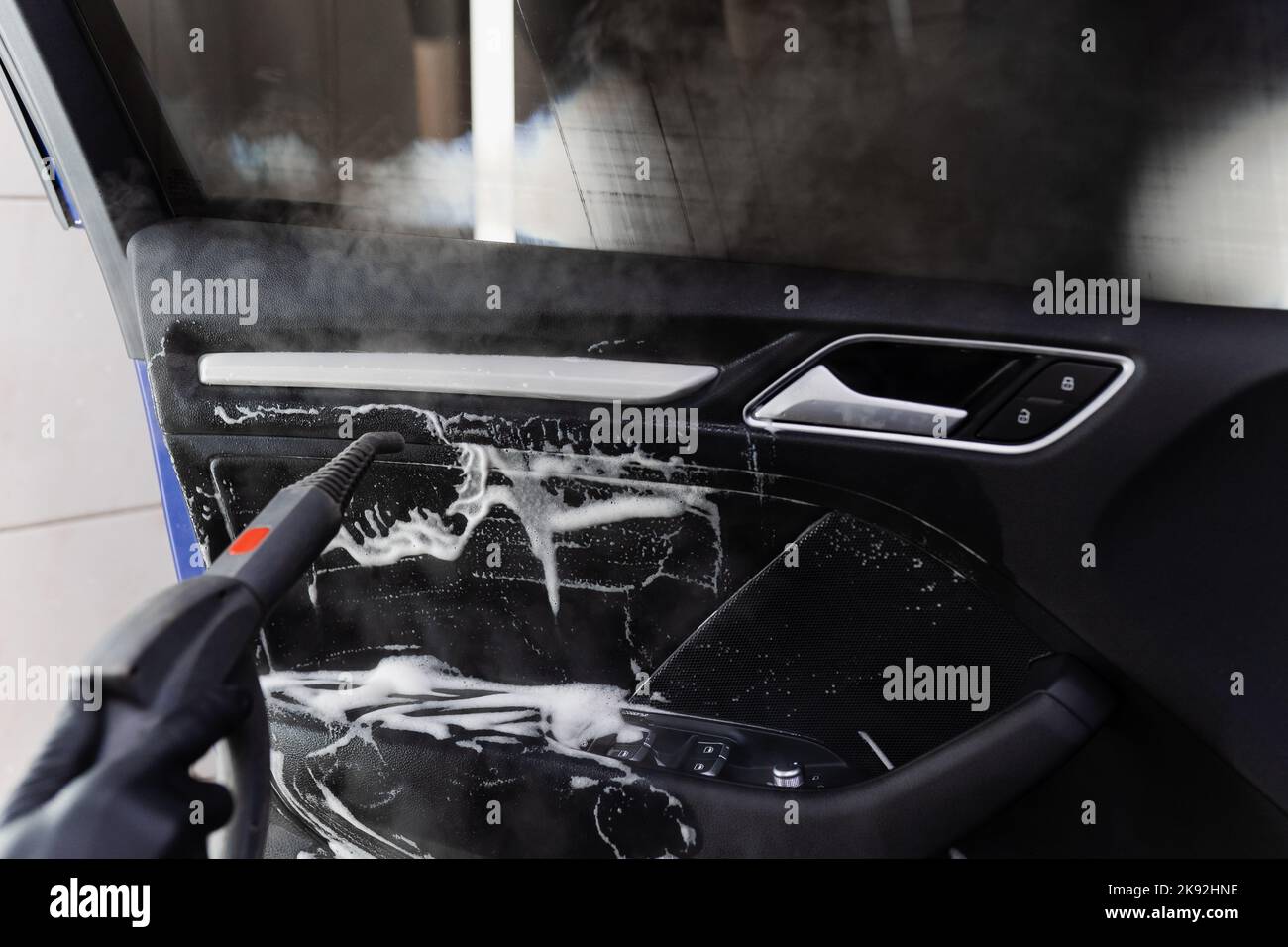 Steam vaping cleaning inside handle of car door after foam washing with ...