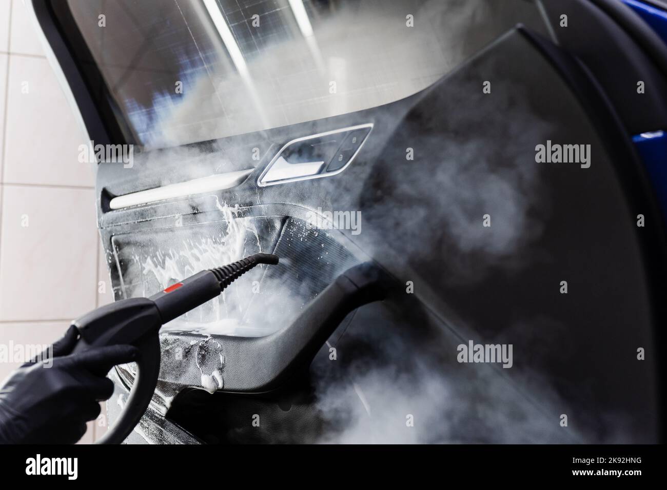 Steam vaping cleaning inside handle of car door after foam washing with ...
