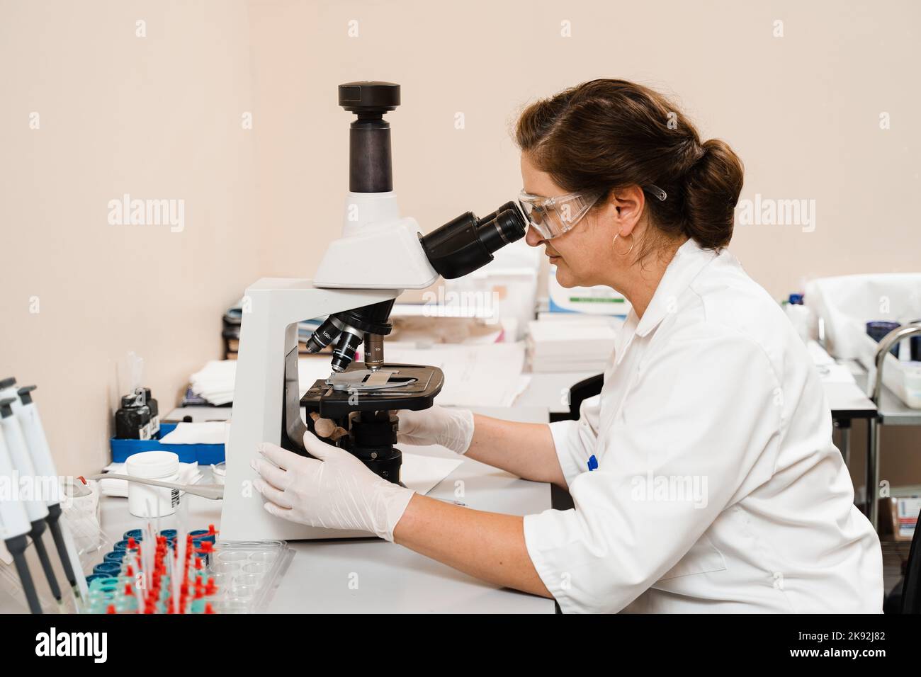 Laboratory assistant looks into microscope and makes blood test in the ...