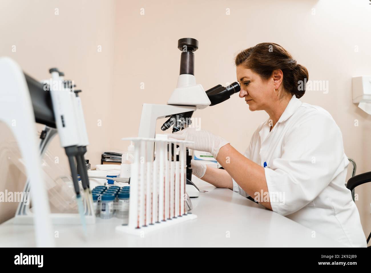Laboratory assistant looks into microscope and makes blood test in the ...