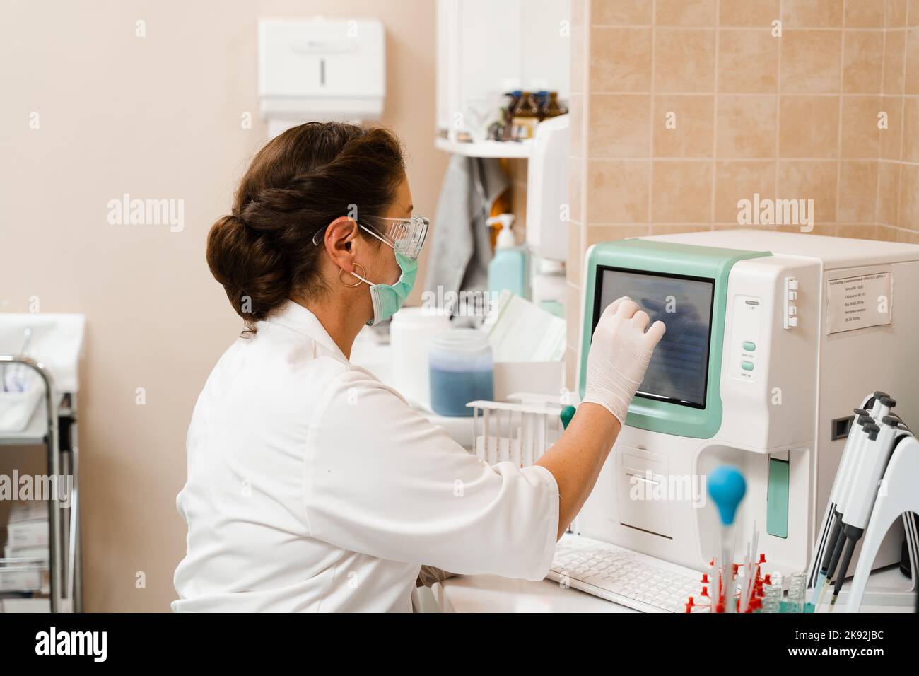 Laboratory assistant works on blood analyzer and makes hematological ...