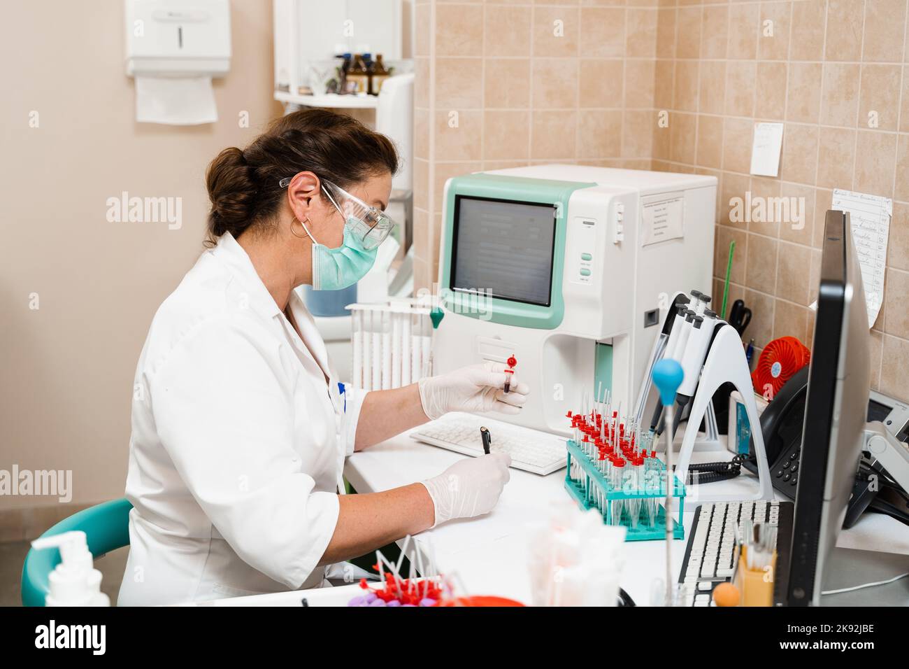 Laboratory assistant works on blood analyzer and makes hematological ...
