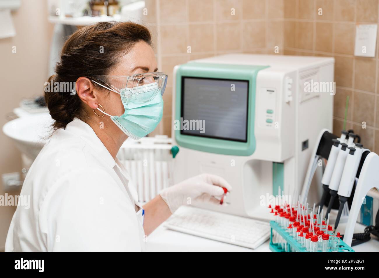 Laboratory assistant works on blood analyzer and makes hematological ...
