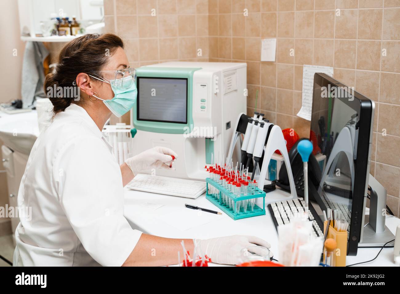 Laboratory assistant works on blood analyzer and makes hematological ...
