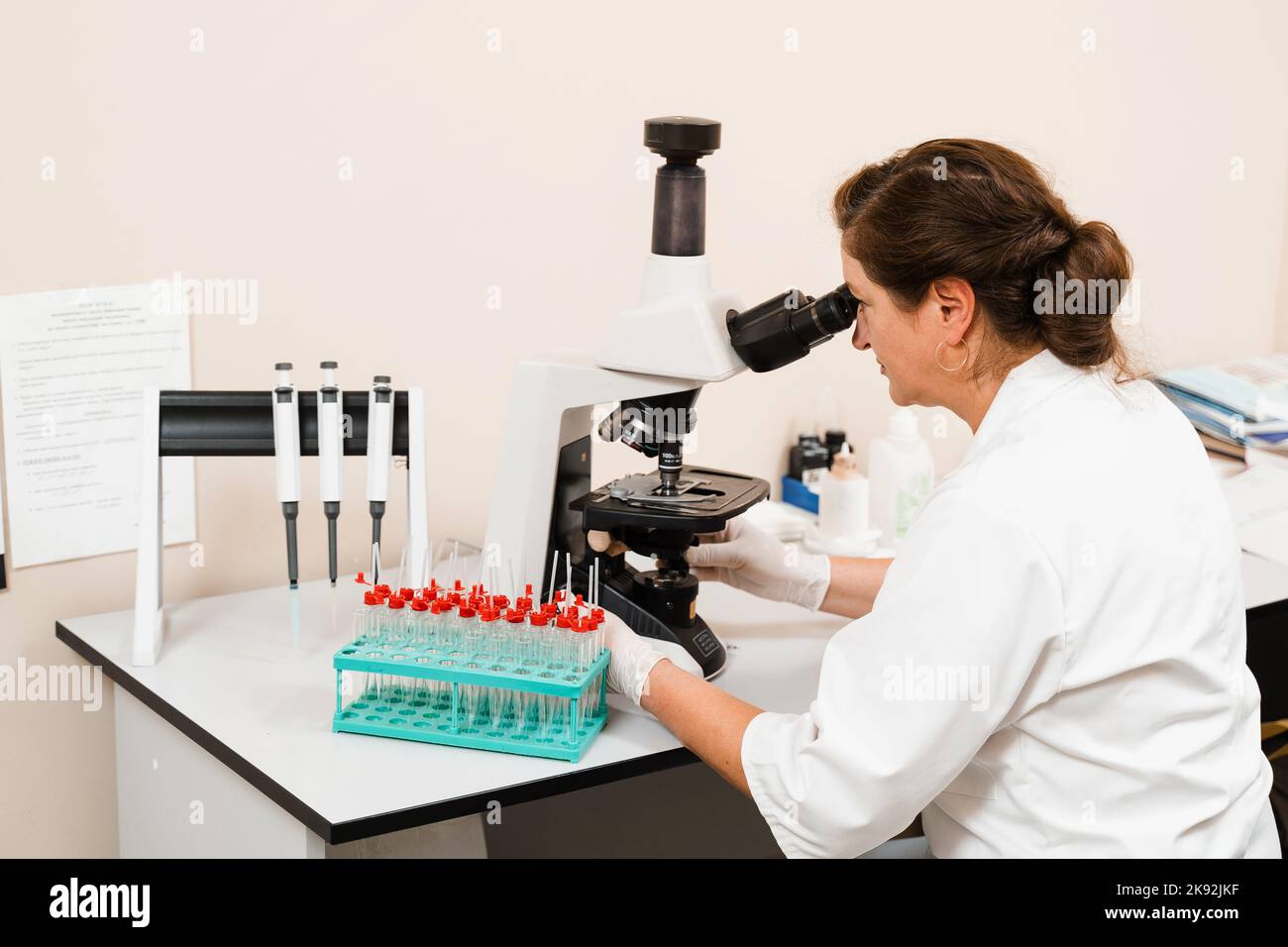 Laboratory assistant looks into microscope and makes blood test in the ...