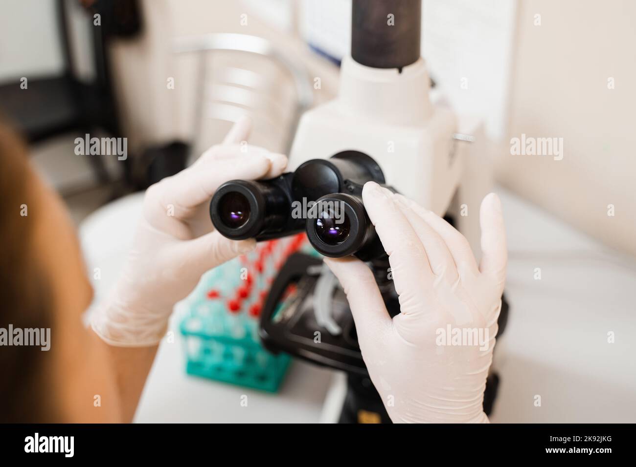 Laboratory assistant looks into microscope and makes blood test in the ...
