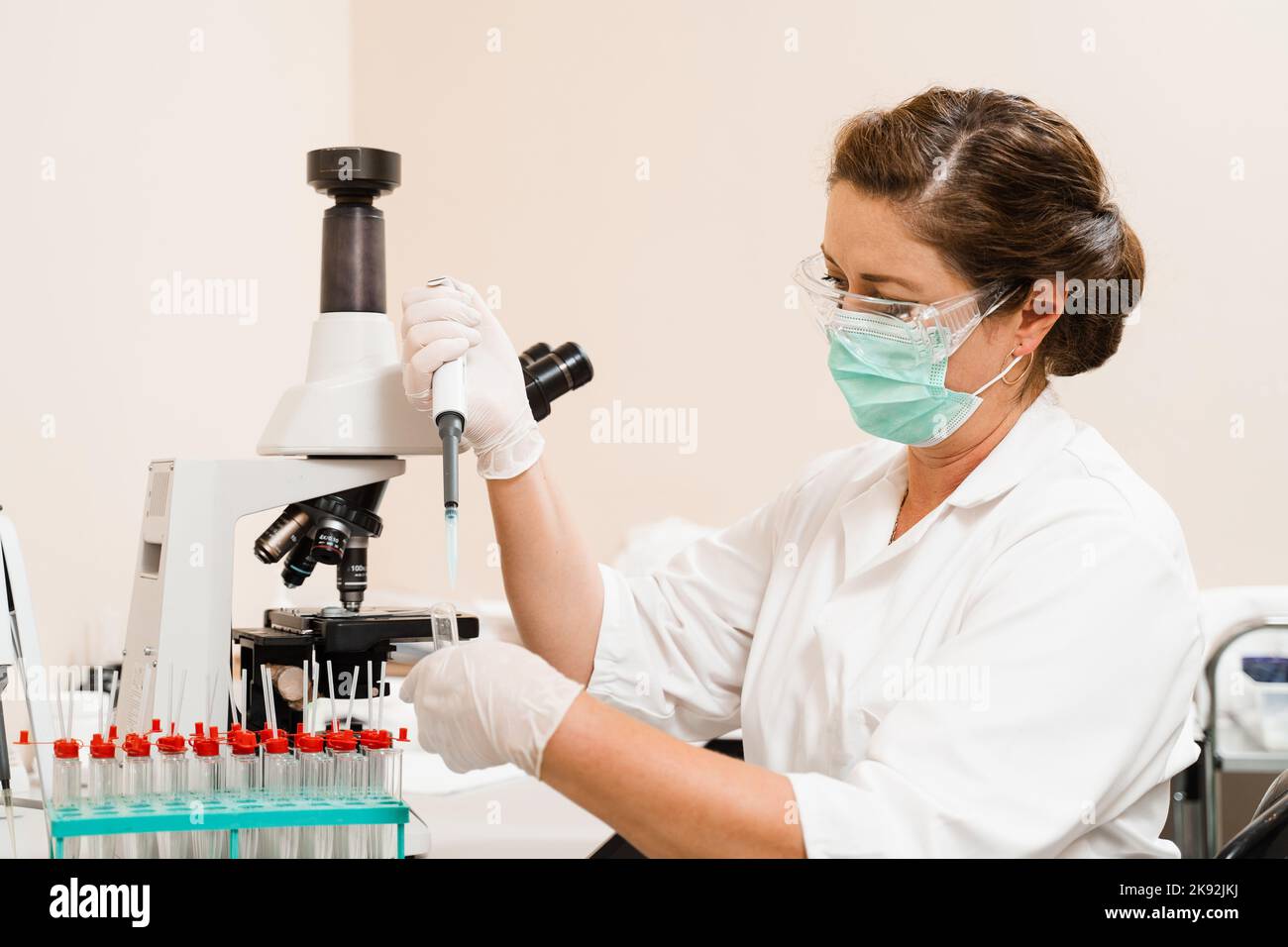 Laboratory assistant with dispenser in laboratory doing blood test ...