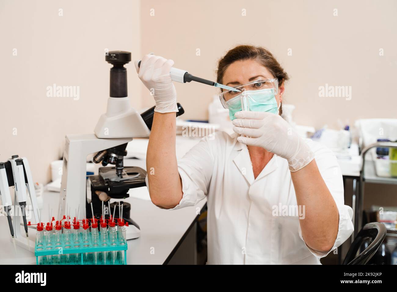 Laboratory assistant with dispenser in laboratory doing blood test ...