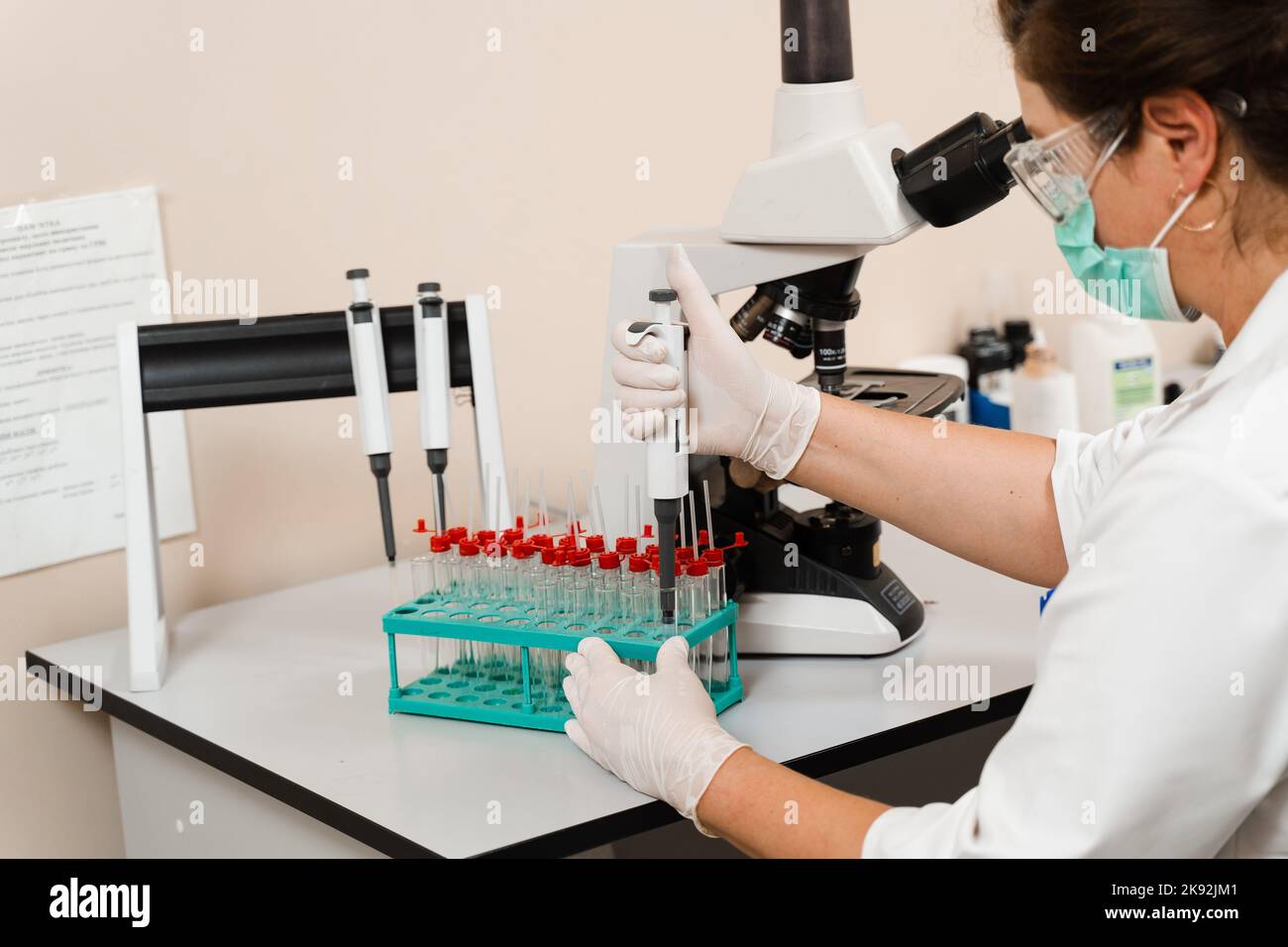 Laboratory assistant with dispenser in laboratory doing blood test ...