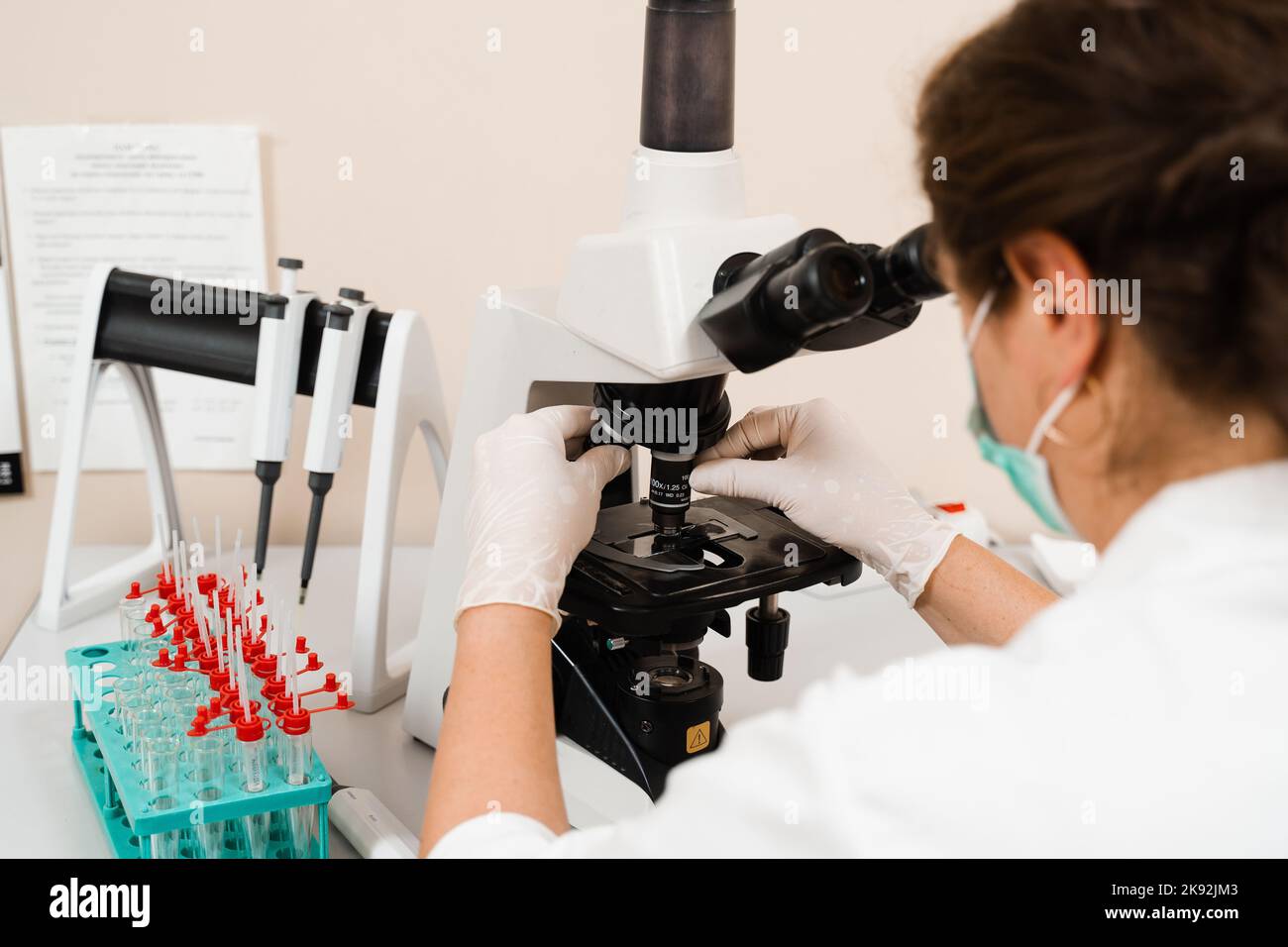 Laboratory assistant looks into microscope and makes blood test in the ...