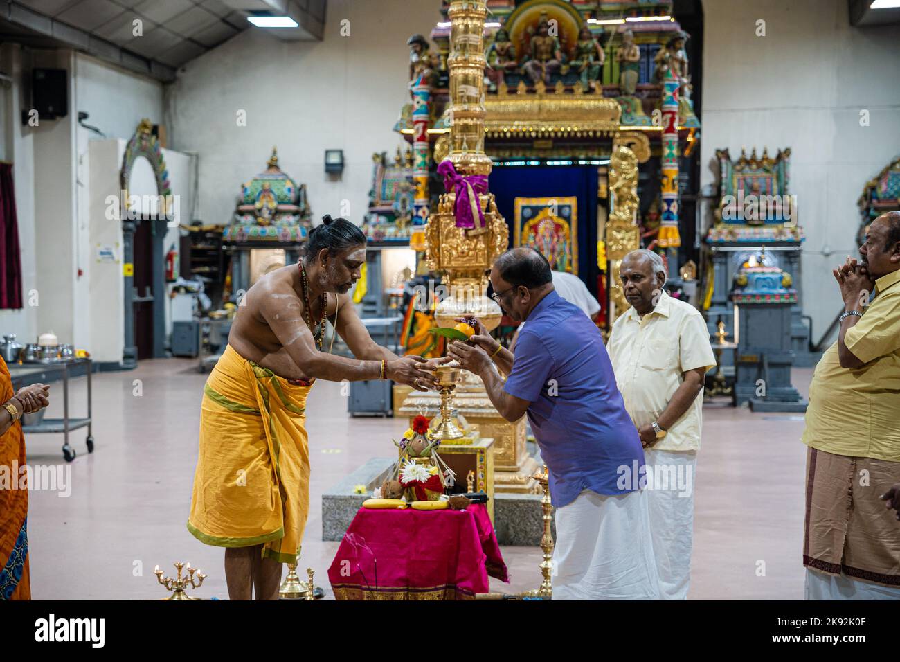A pandit extends offerings that were blessed during a puja ceremony to ...