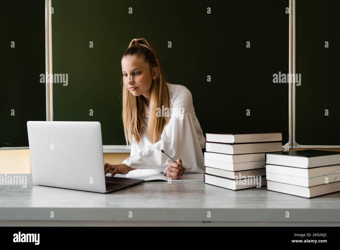 Education. Schoolgirl typing on laptop and study online at school board ...