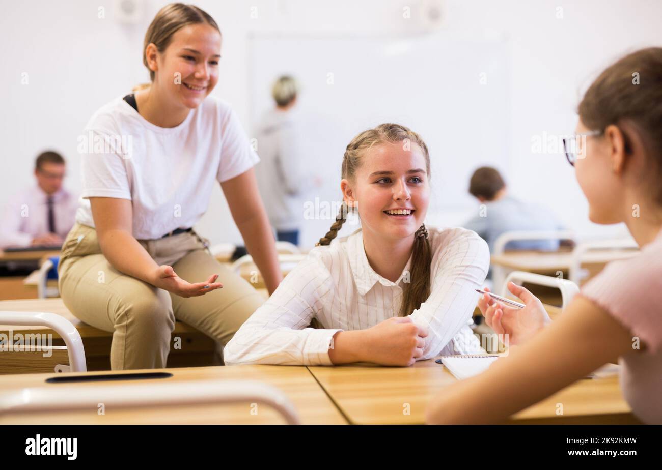 Teenage schoolgirls friendly talking during recess in classroom Stock ...