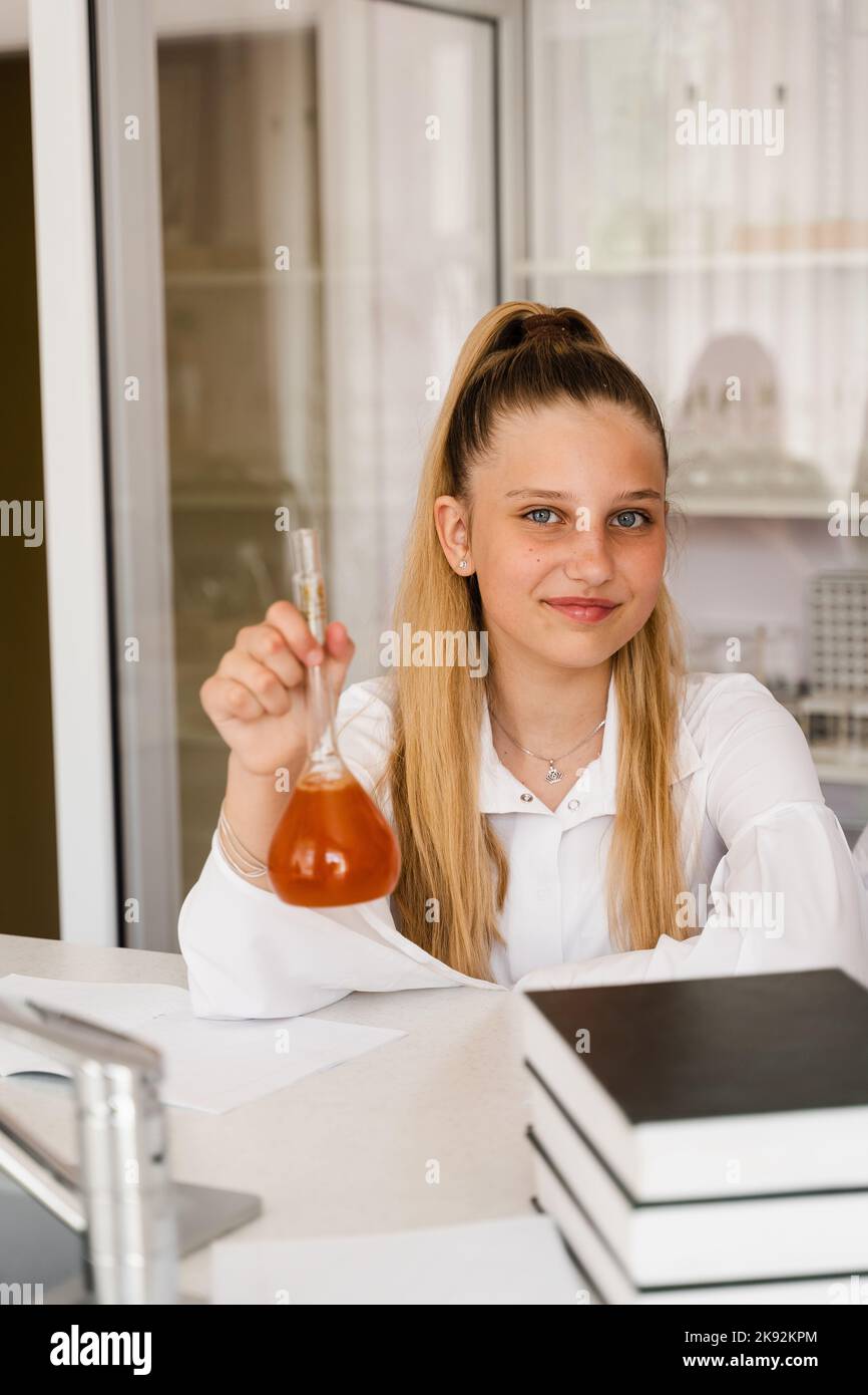 Chemistry lesson at school. Girl with flask is studying in chemistry ...