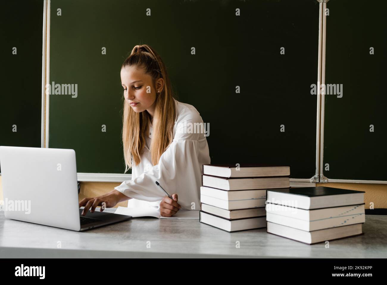 Education. Schoolgirl typing on laptop and study online at school board ...