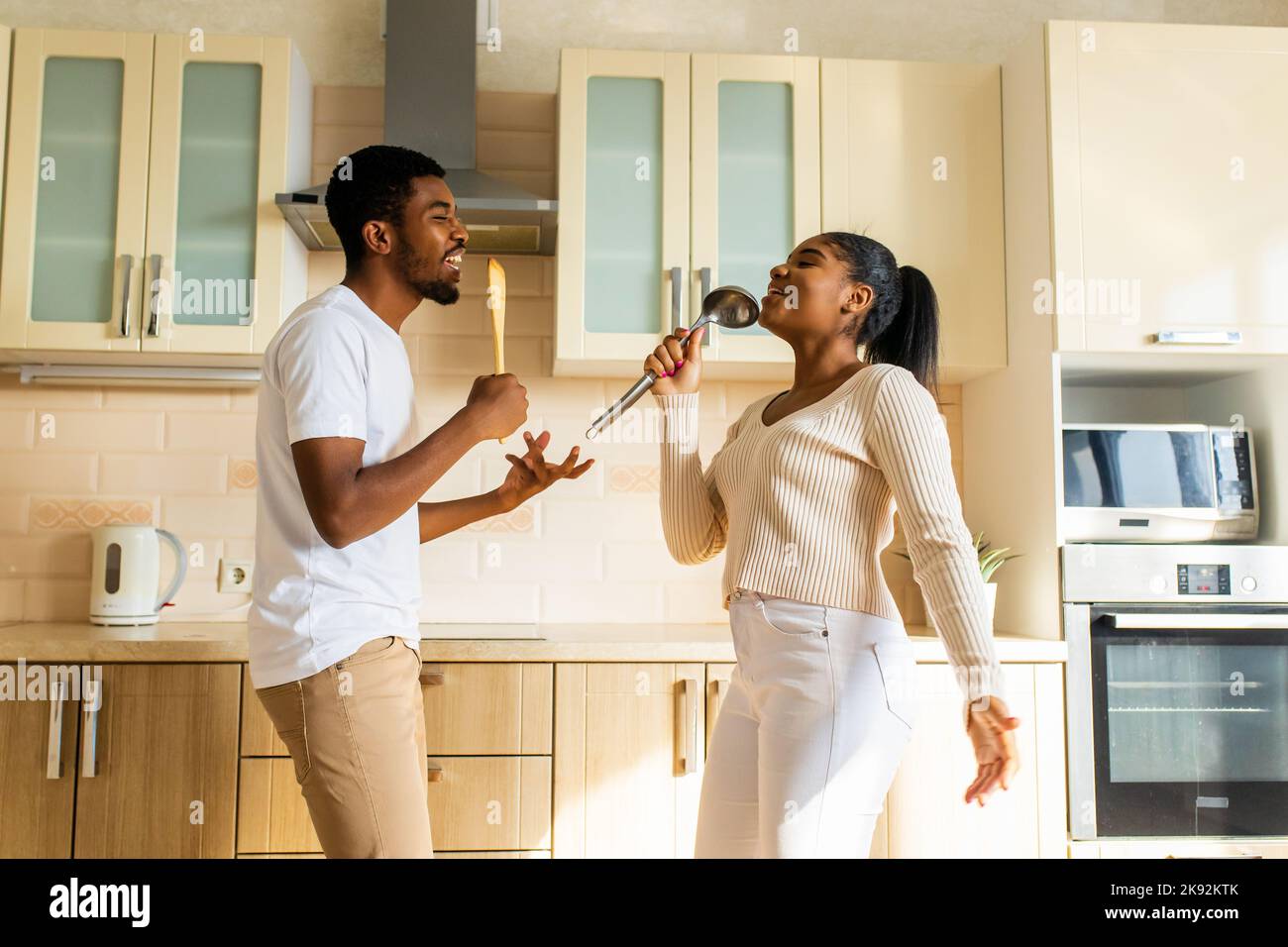 hispanic couple singing together holding a ladle like a microphone in ...