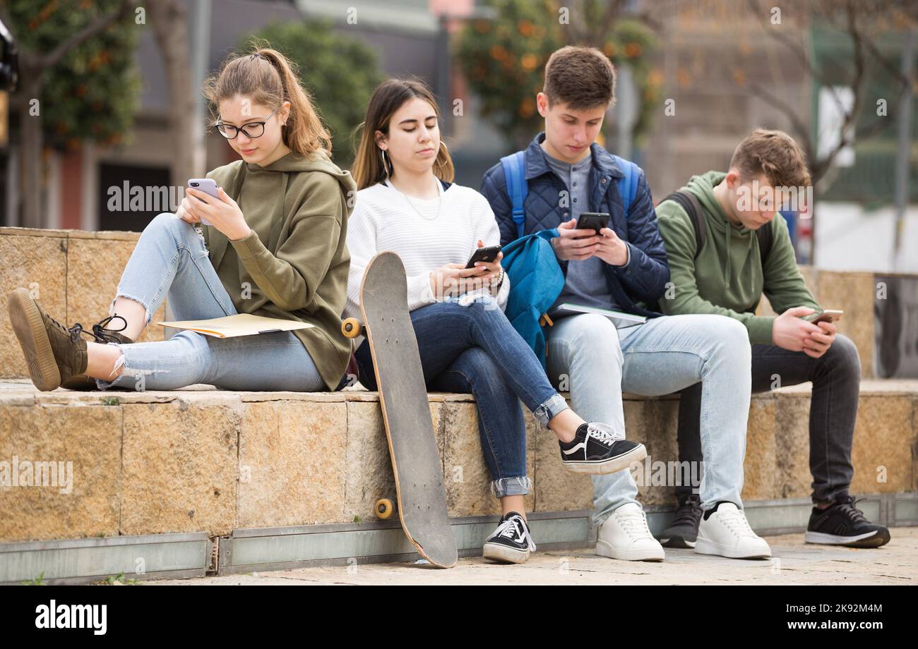 Four teenagers enthusiastically look at the screens of their ...