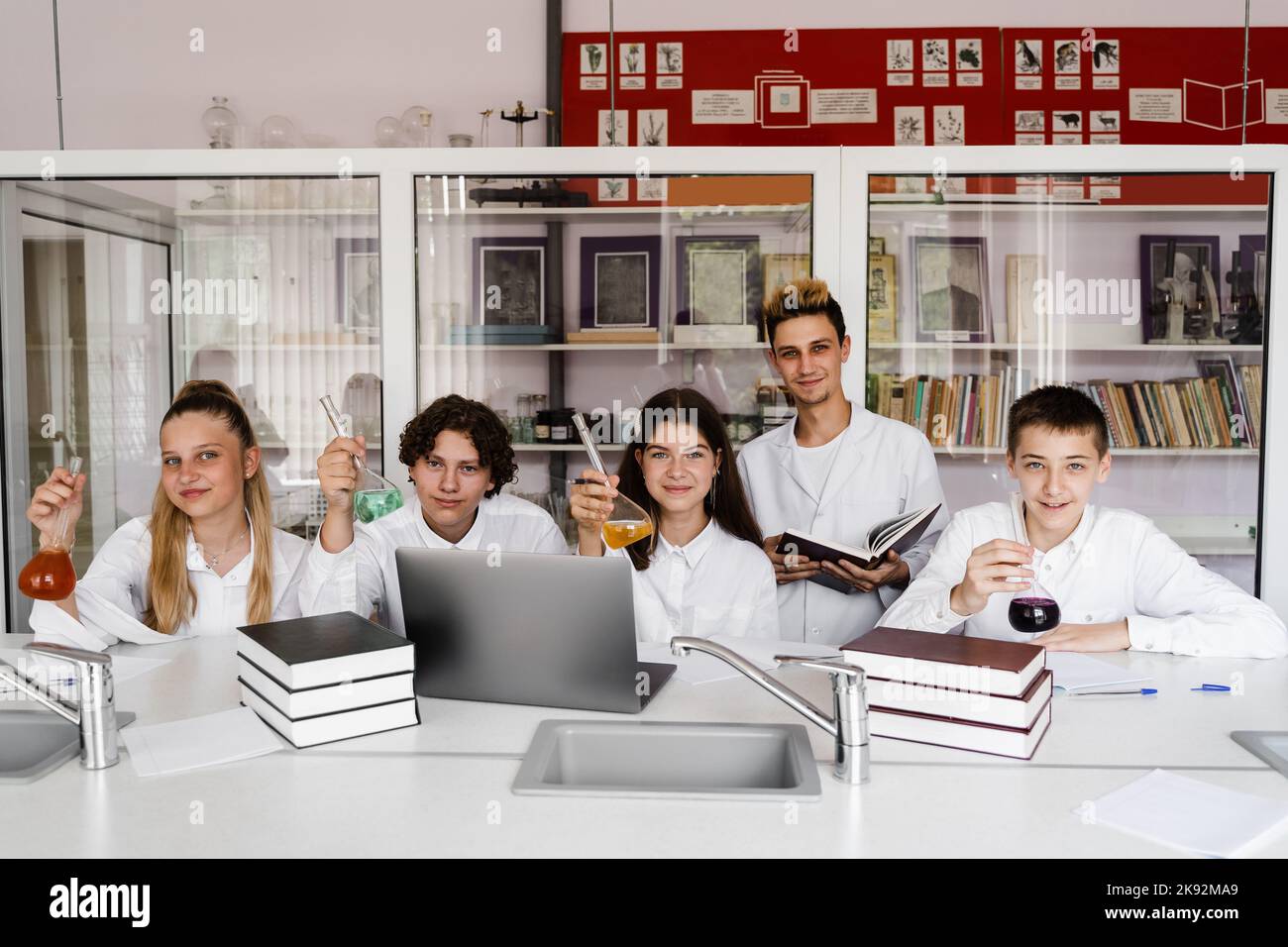 Cheerful company of classmates friends holds test tubes with colored ...