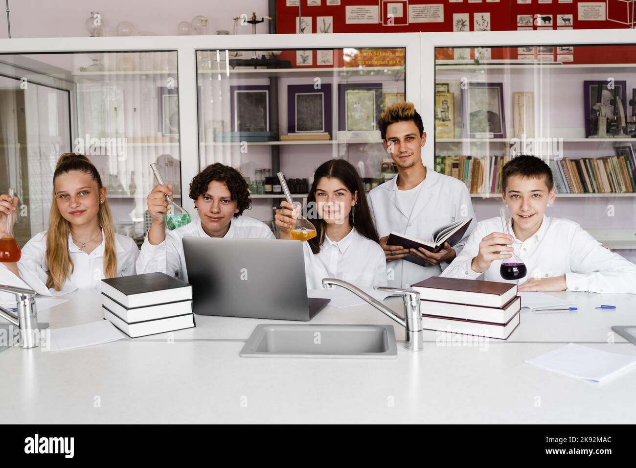 Cheerful company of classmates friends holds test tubes with colored ...