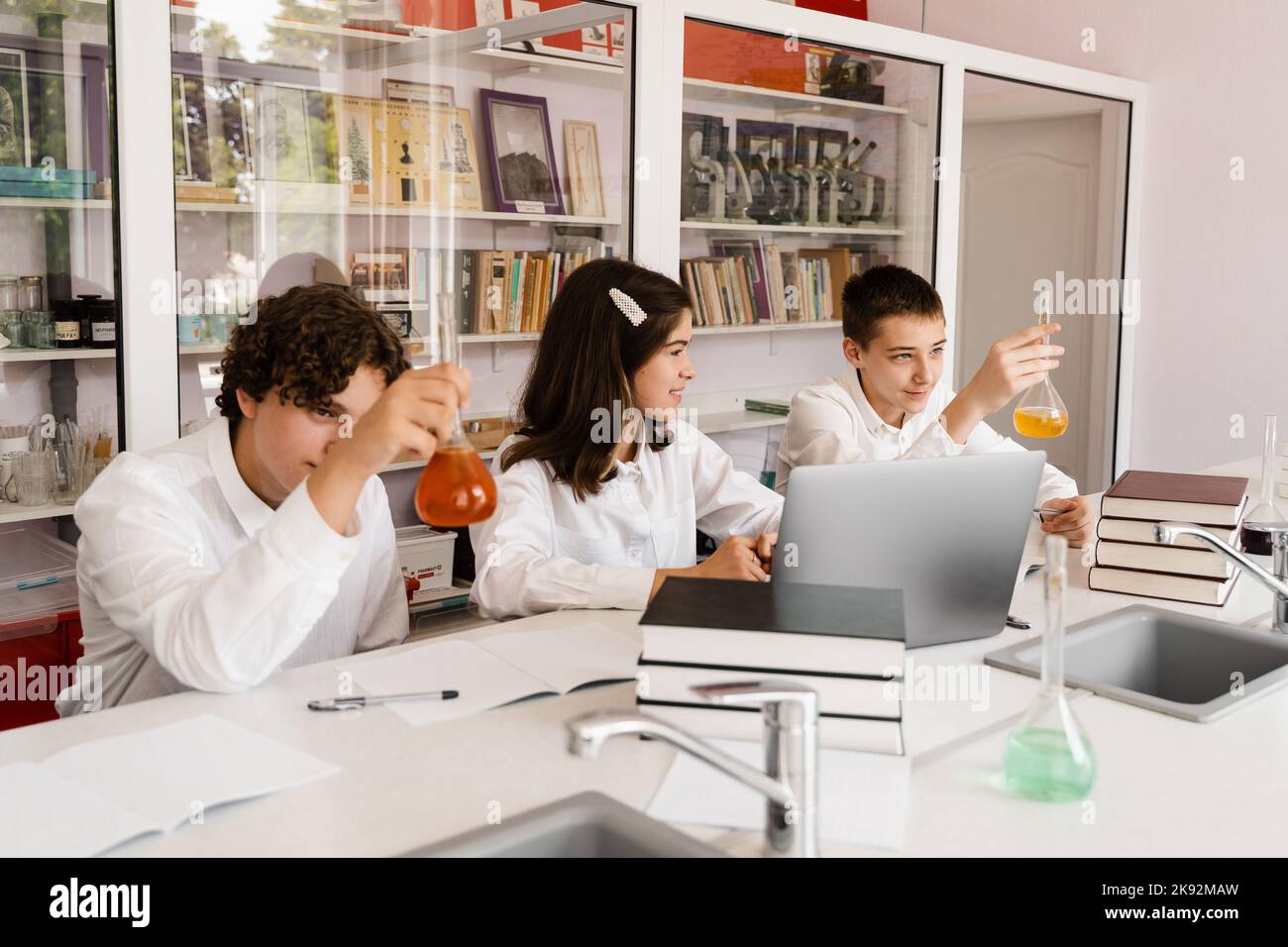 Pupils holding flasks with liquid for experiments in laboratory ...