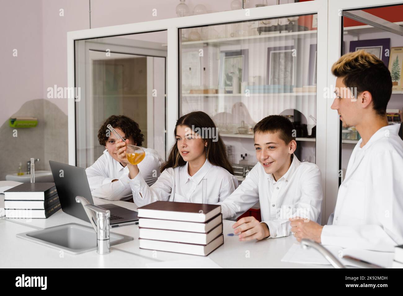 School teacher gives chemistry lesson to children in a laboratory with ...