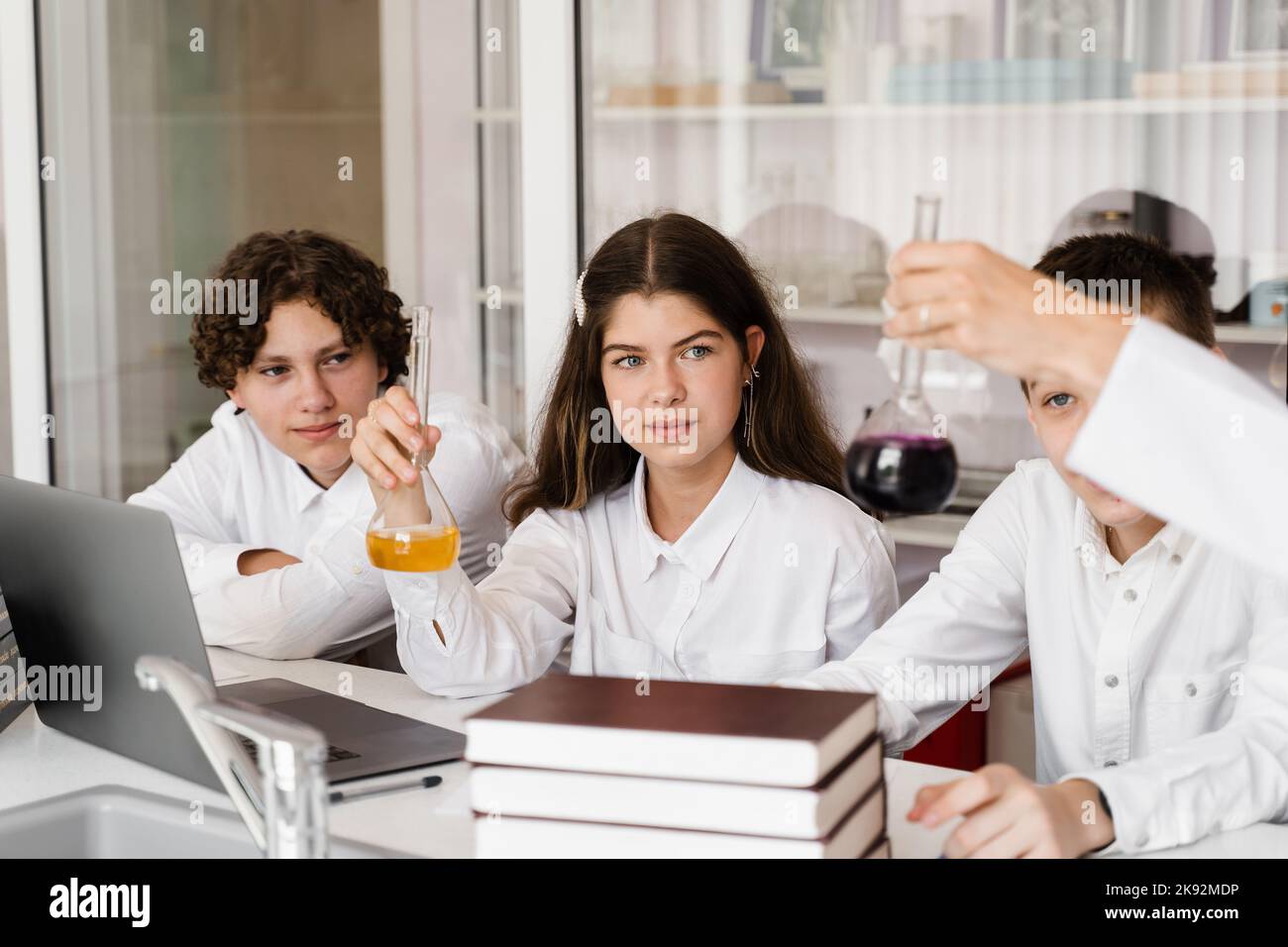 School teacher gives chemistry lesson to children in a laboratory with ...