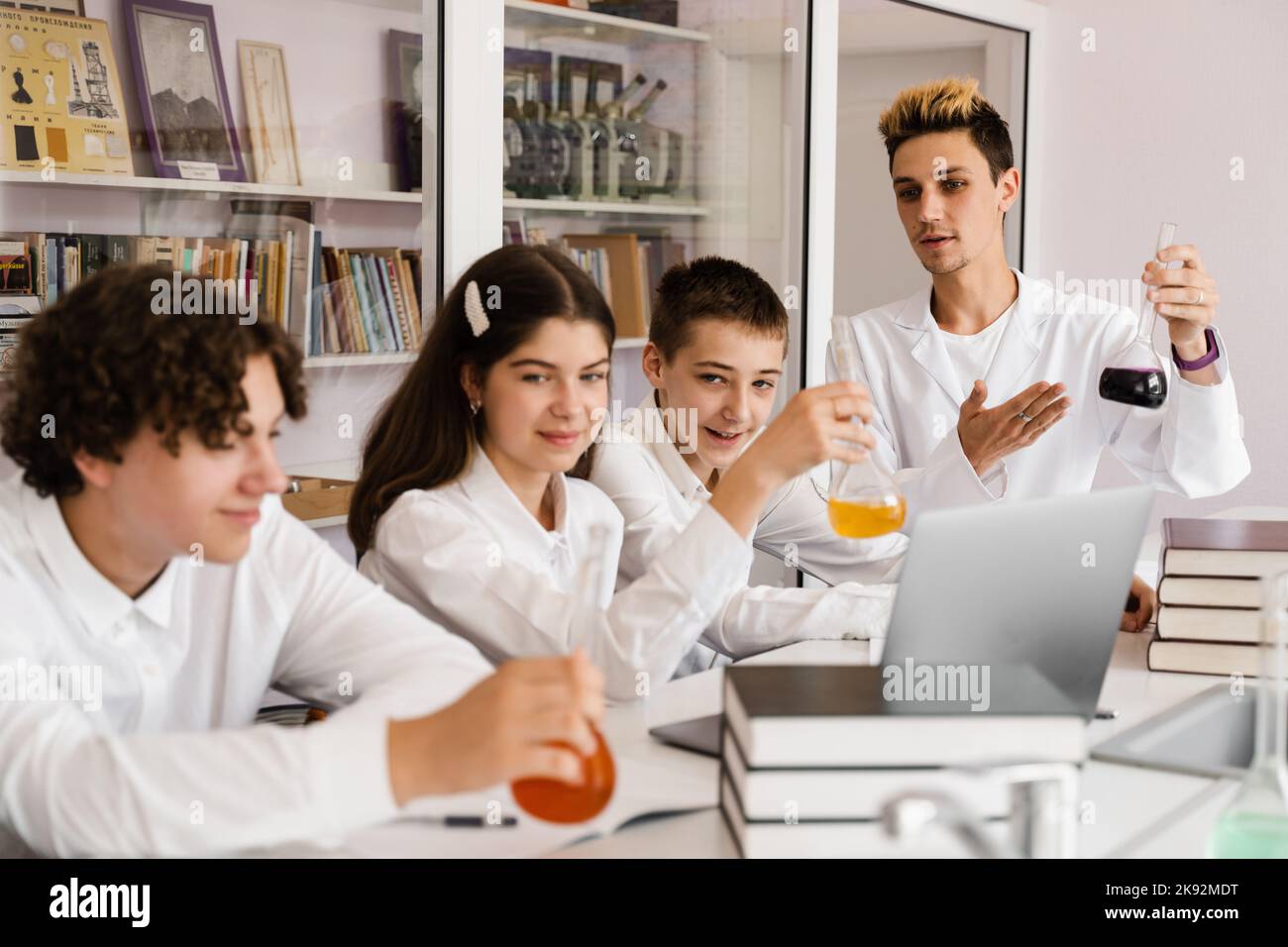 School chemistry teacher shows children flasks with liquids for experiments in the laboratory ...