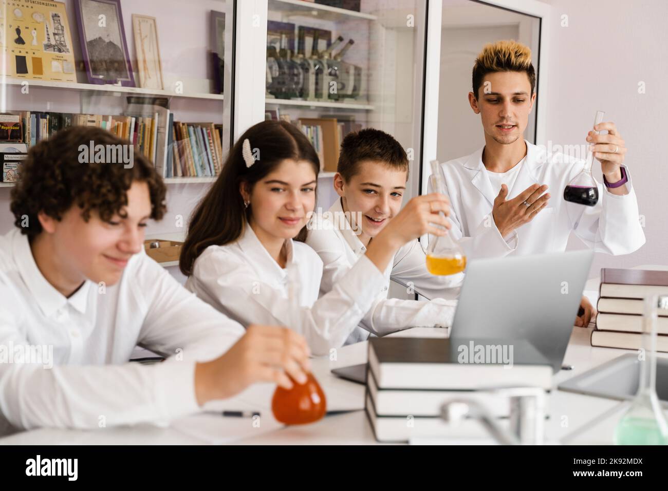 School chemistry teacher shows children flasks with liquids for ...