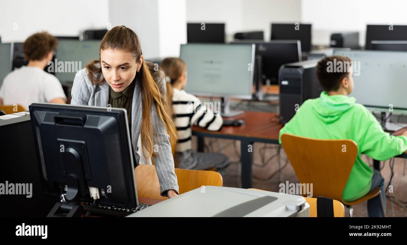 Female teacher working on computer in class Stock Photo - Alamy